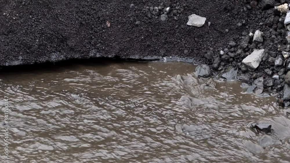 Glacier with ash in the ice with melted water and Icelandic landscape ...