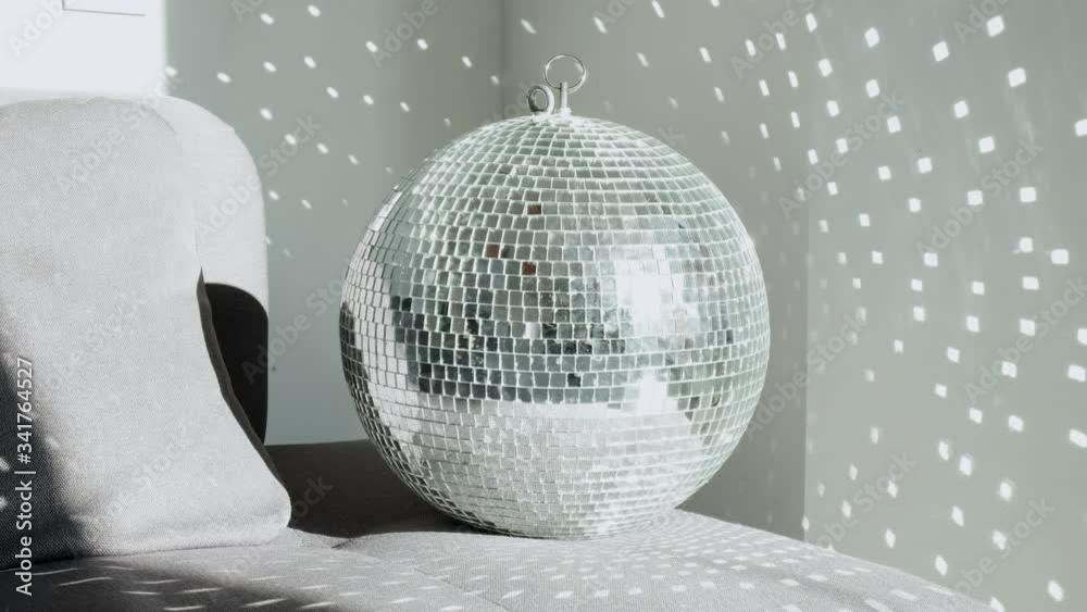 man's hand rotating vintage disco ball in sun beam light with bright ...
