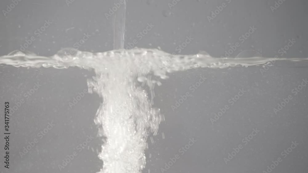 Water poured into tank, many air bubbles rising to surface, gray ...