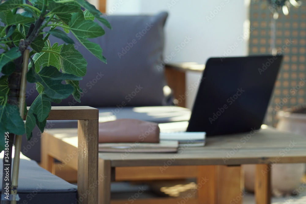 view of a cozy outdoor workplace with a laptop on a table of a sitting ...