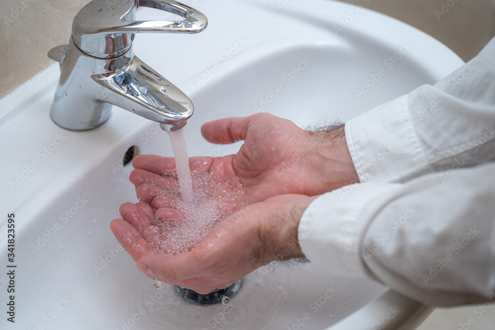 Man washing hands with soap and water in clean bathroom ...