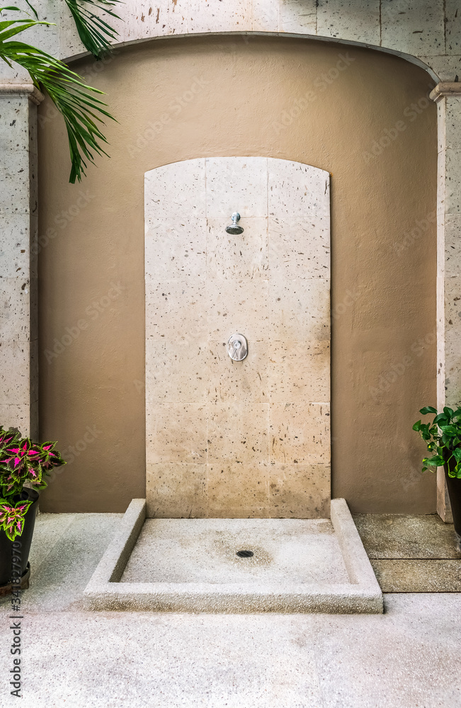 Tropical outdoor shower , natural stone wall, garden setting, with ...