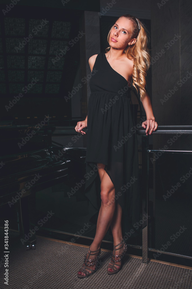 pretty woman in black evening dress , with hair style posing near a ...