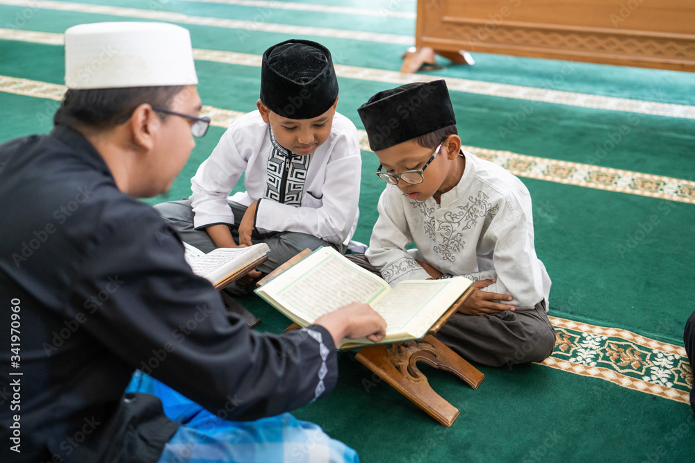 teacher is teaching muslim kid how to read holy quran in the mosque ...