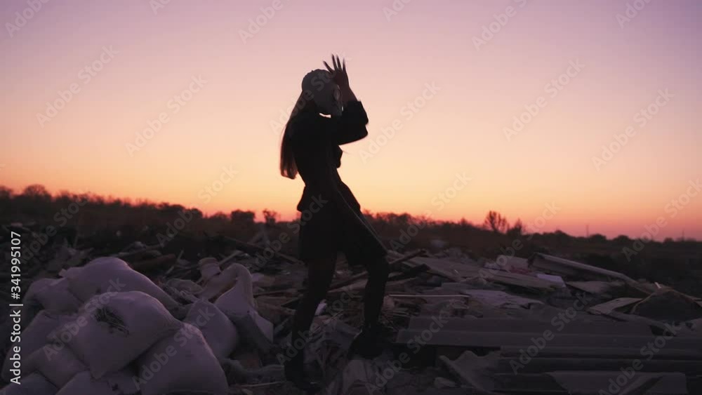 girl in a black dress, in tights and a gas mask dancing at sunset on ...
