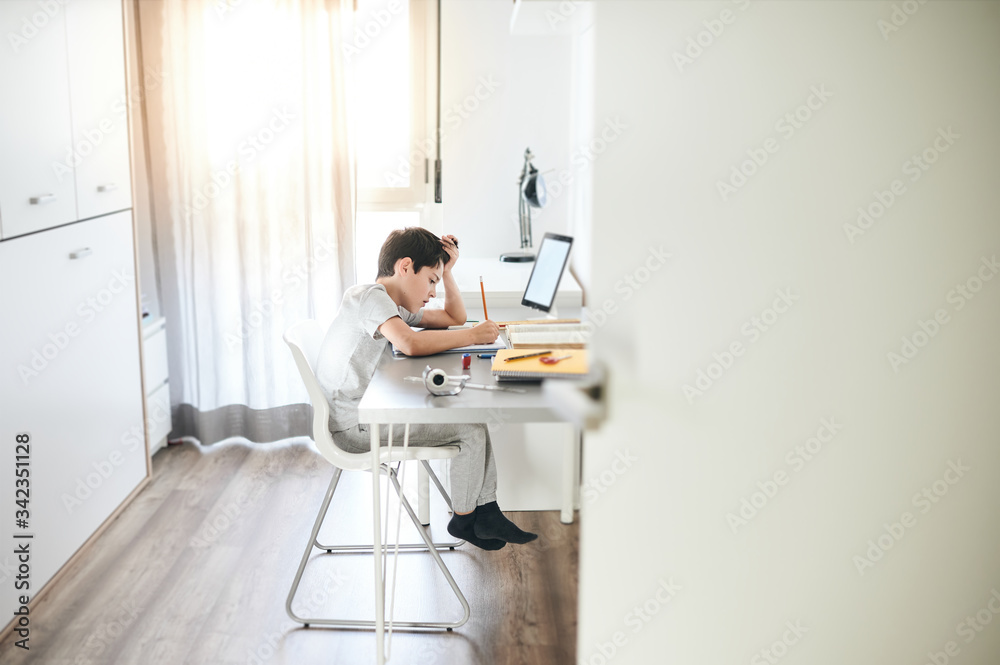 Stress kid doing homework.Boy at study table doing homework with stress ...