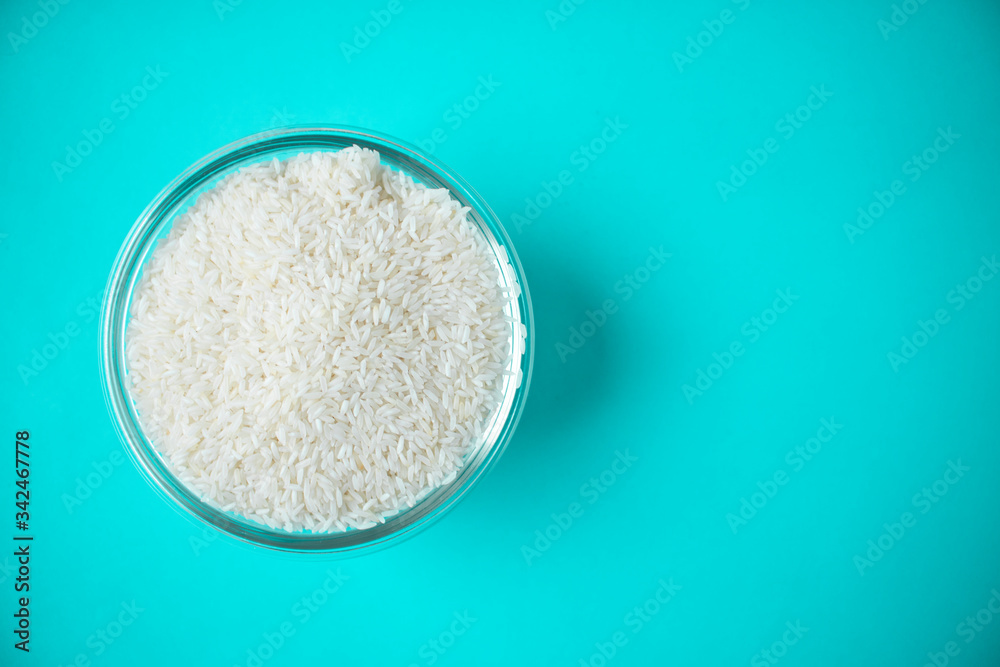 Rice bowl, uncooked rice, grains on sky blue background, isolated with ...