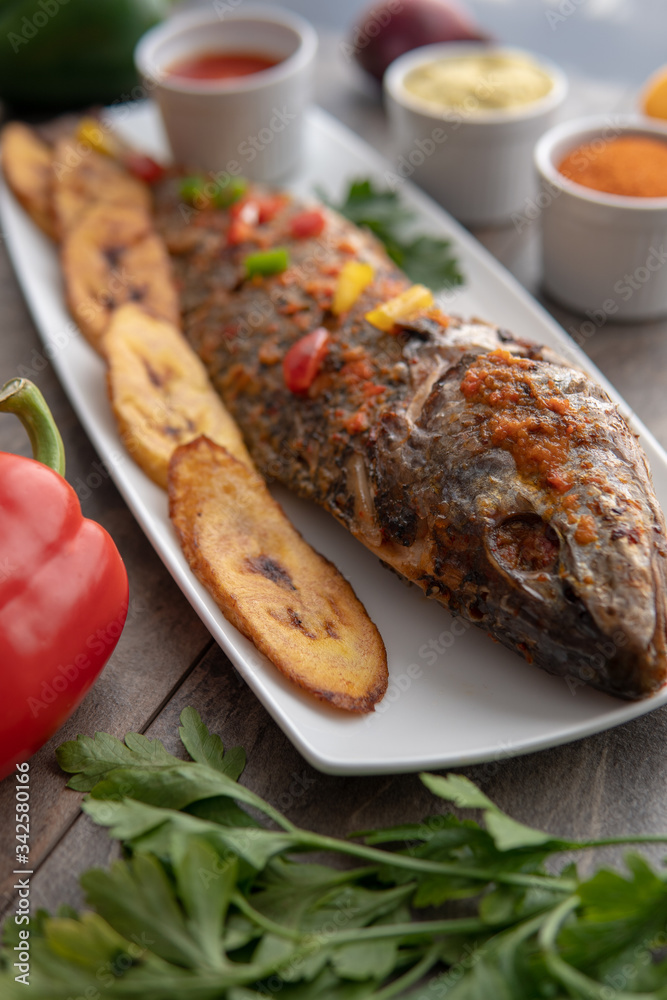 Grilled fish curry with plantain and salad. African national dish ...