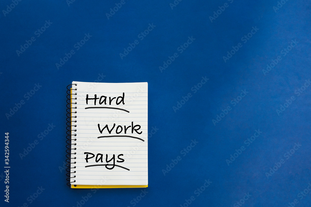 An office notebook with hard work pays written in it laying on top of a ...