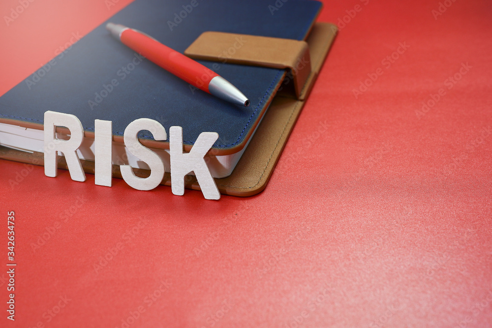 Risk wording on a notebook isolated on a red background. Risk ...