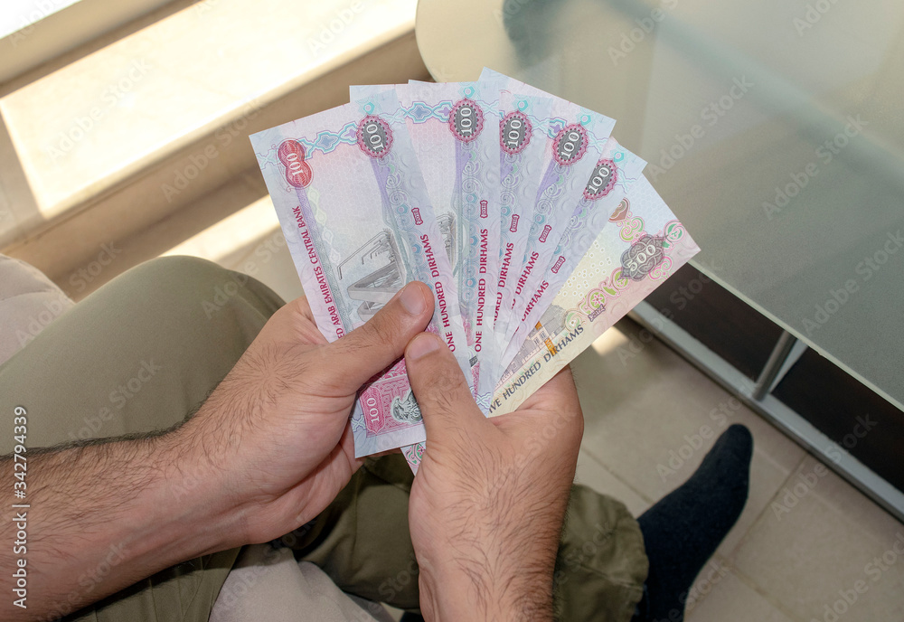 UAE national currency. UAE money banknotes. Young man holds in hands ...