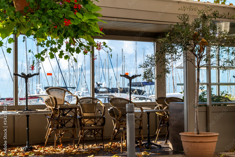 A small, empty covered patio with tables and chairs stacked fills with ...
