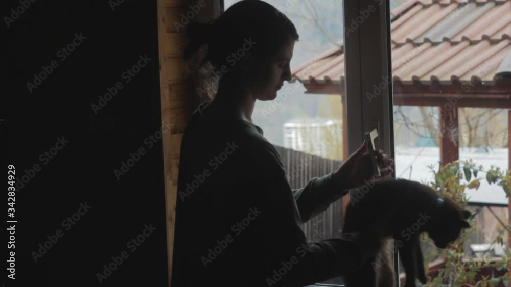 Silhouette of a girl opens a window and takes a breath of fresh air ...