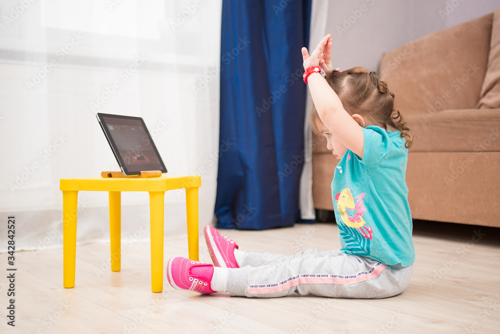 little girl with a watch on her hand at home in an online training ...