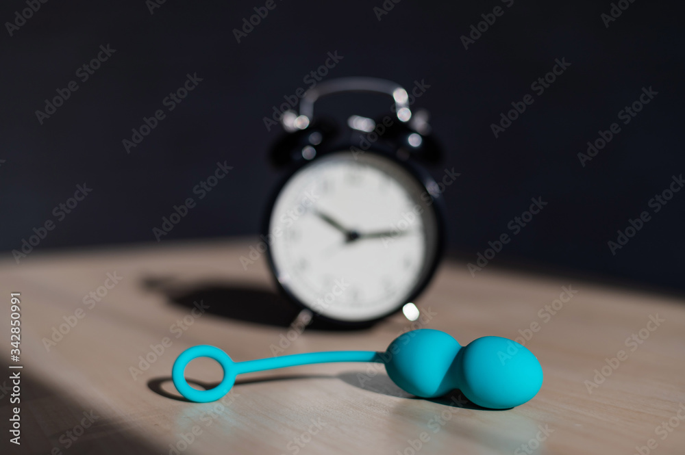 Alarm clock and vibrator on the table. Time for training intimate ...