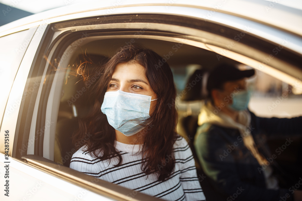 A girl and a boy driving in a car during coronavirus quarantine wearing ...