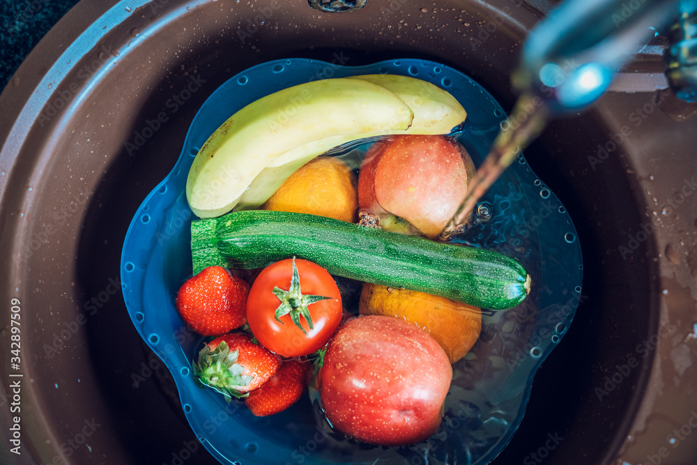 Blue basin full of fruits and vegetables with tap water in the kitchen ...