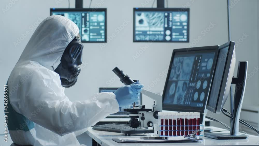 Scientist in protection suits and masks working in research lab using ...