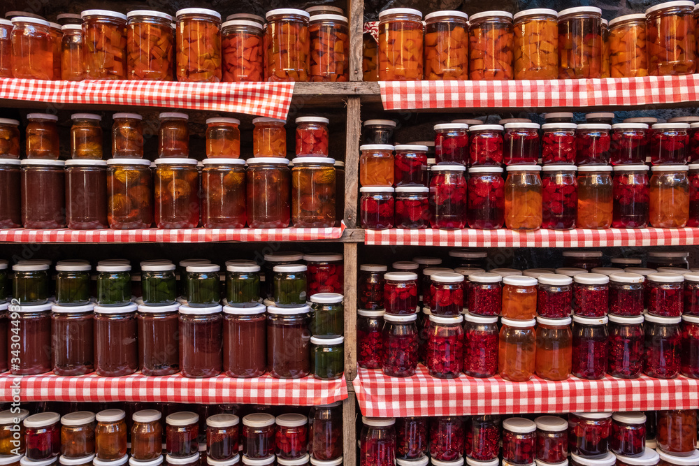 Glass jars with various types of natural delicious jam stand in a row ...