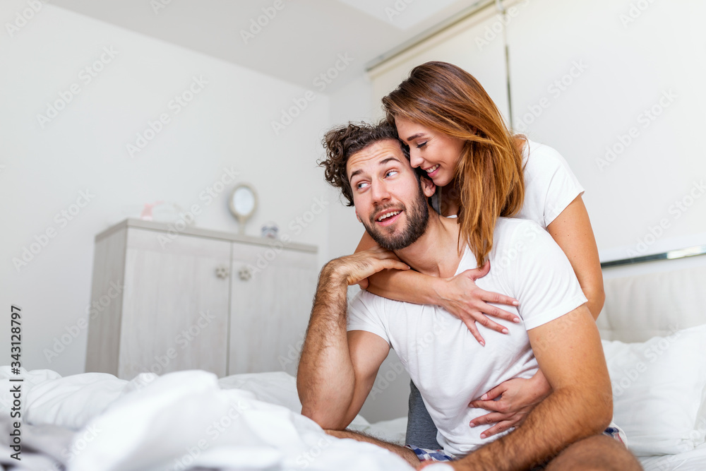 Woman embracing her partner in bed, Happy couple in bed showing ...