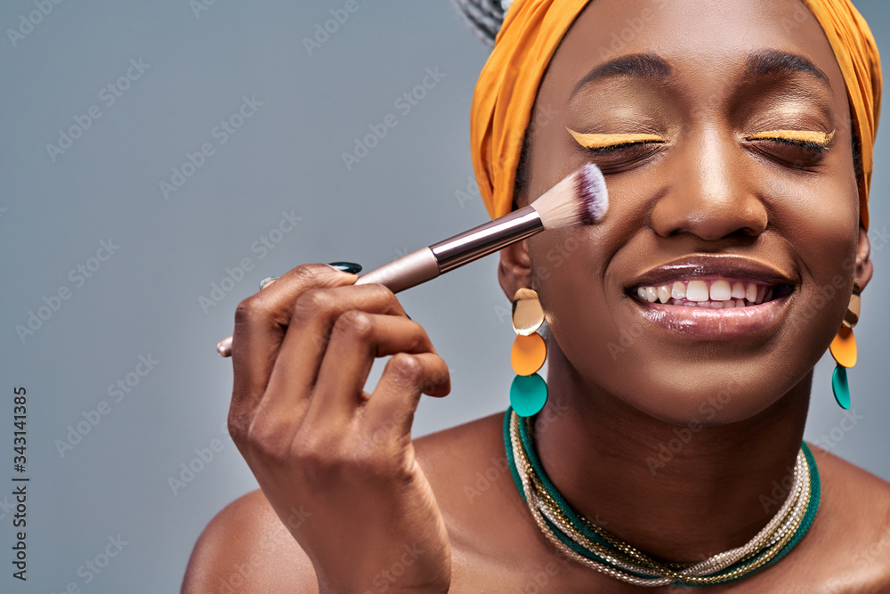 Young African woman in Studio doing body care and applying makeup ...