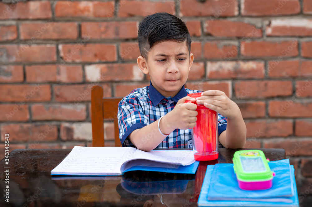 Primary school student drinking water with red water bottle while ...