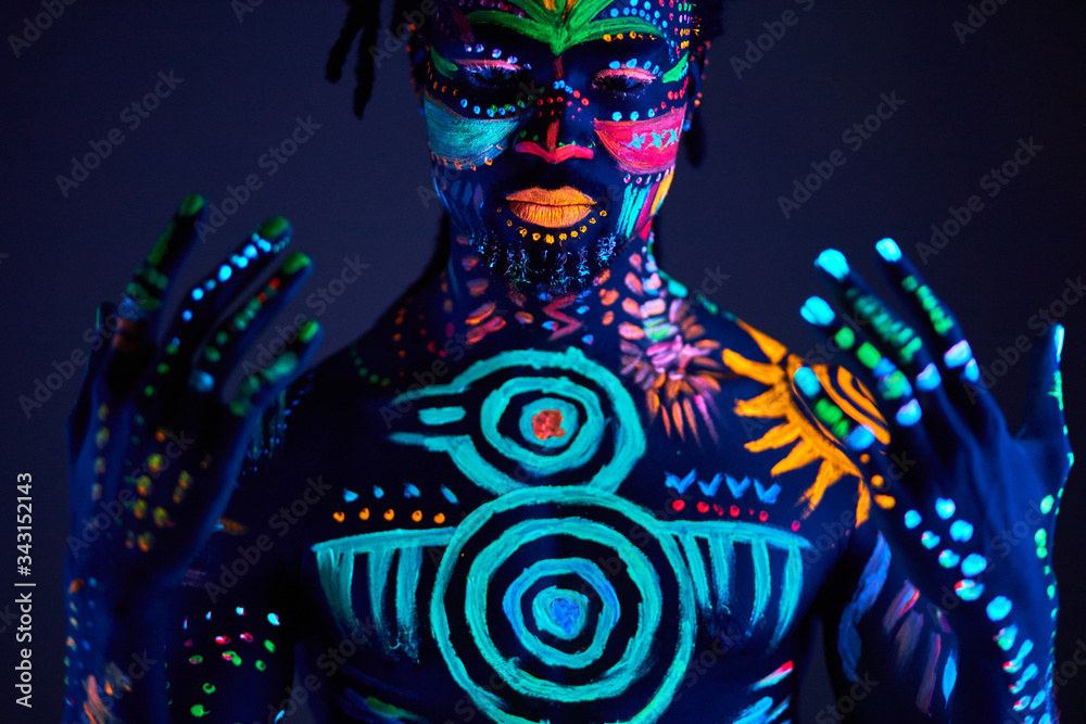 Conceptual portrait of young african man painted in glowing fluorescent ...