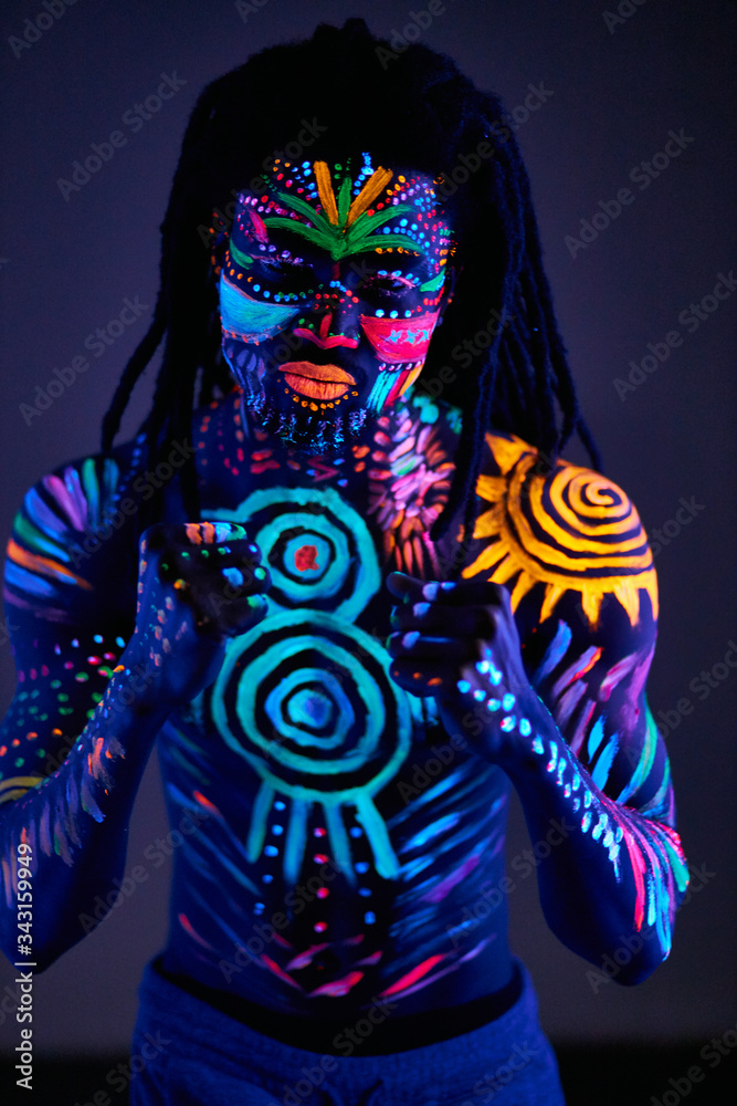 strong muscular man with fluorescent prints in the pose of fighter ...