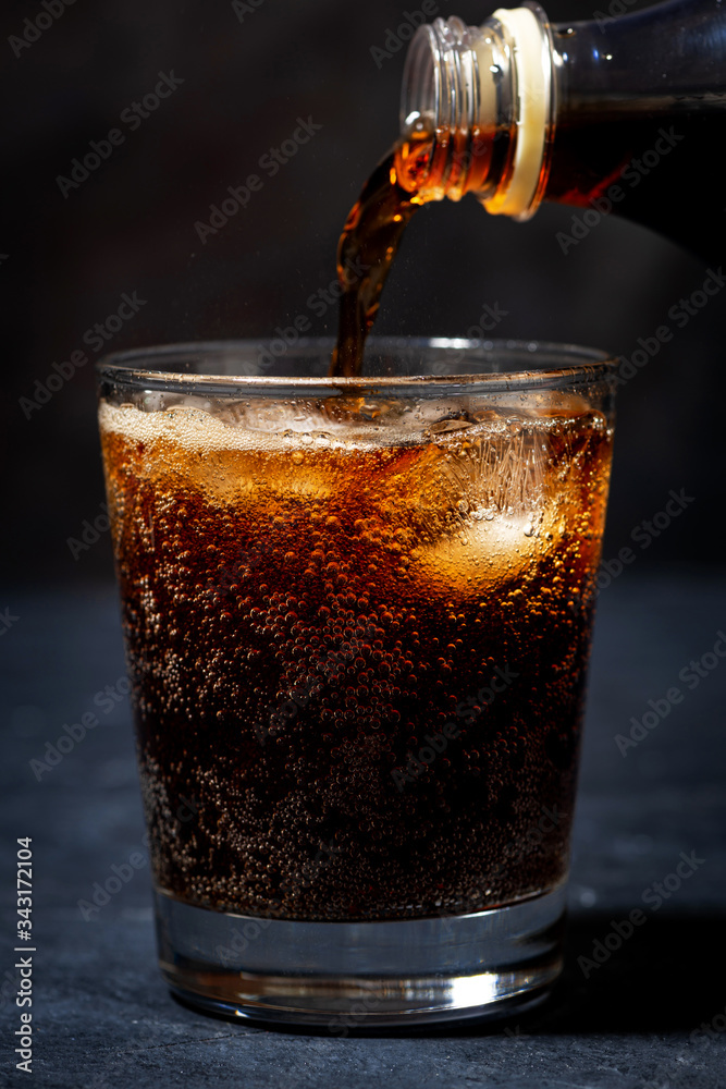 Coca cola is poured into a glass from bottle Stock Photo | Adobe Stock