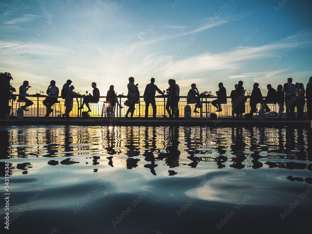 silhouette of people at a after work pool party in the sunset with ...