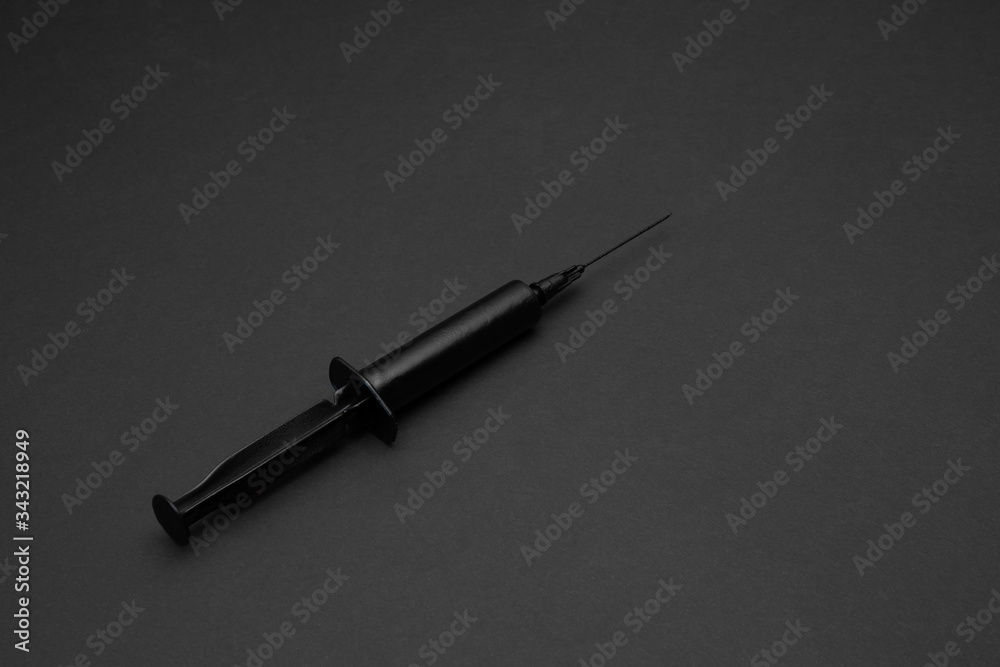 Black matte syringe on a black background. Copy space. Dark mode ...