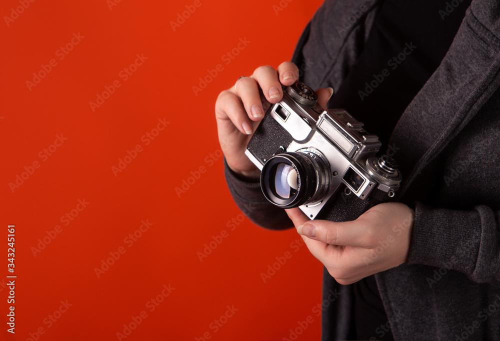 The vintage camera of the old model is in the hands of a girl. In the ...