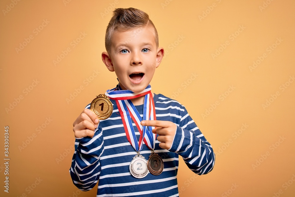 Young little caucasian winner kid wearing award competition medals over ...