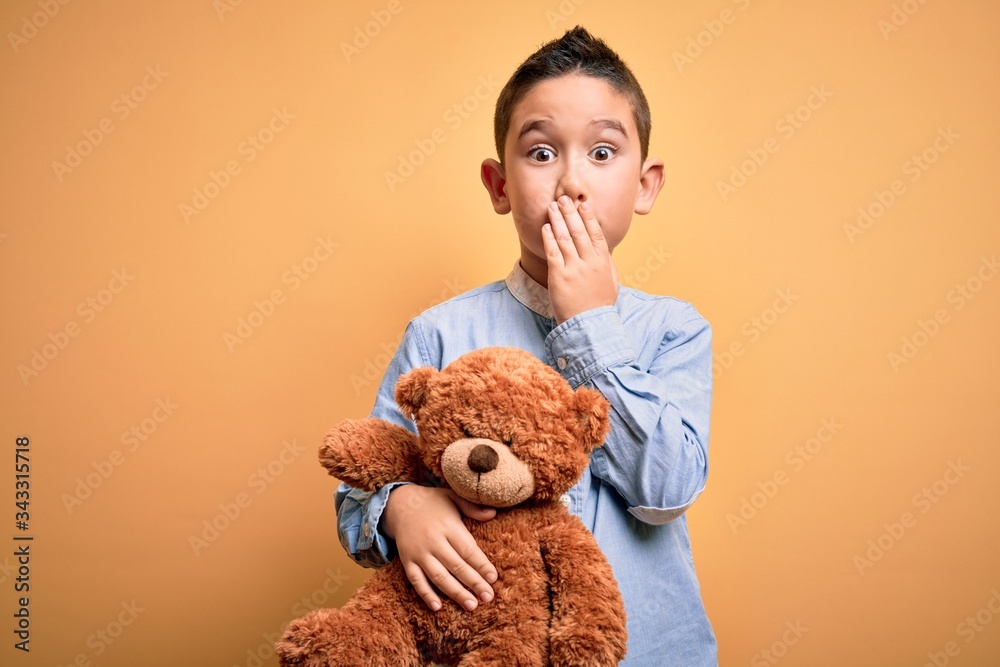 Young little boy kid hugging teddy bear stuffed animal over yellow ...