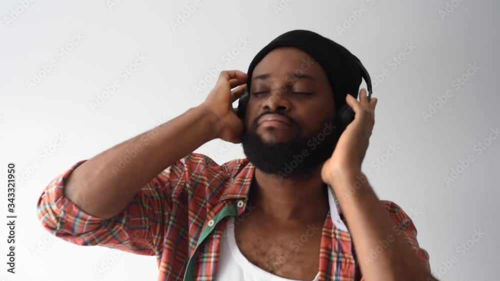 A handsome black man wearing a black hat and headphones, listening to ...