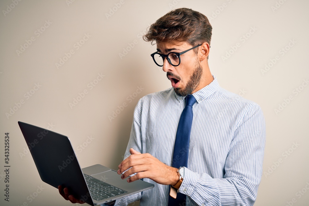 Young businessman wearing glasses working using laptop standing over ...