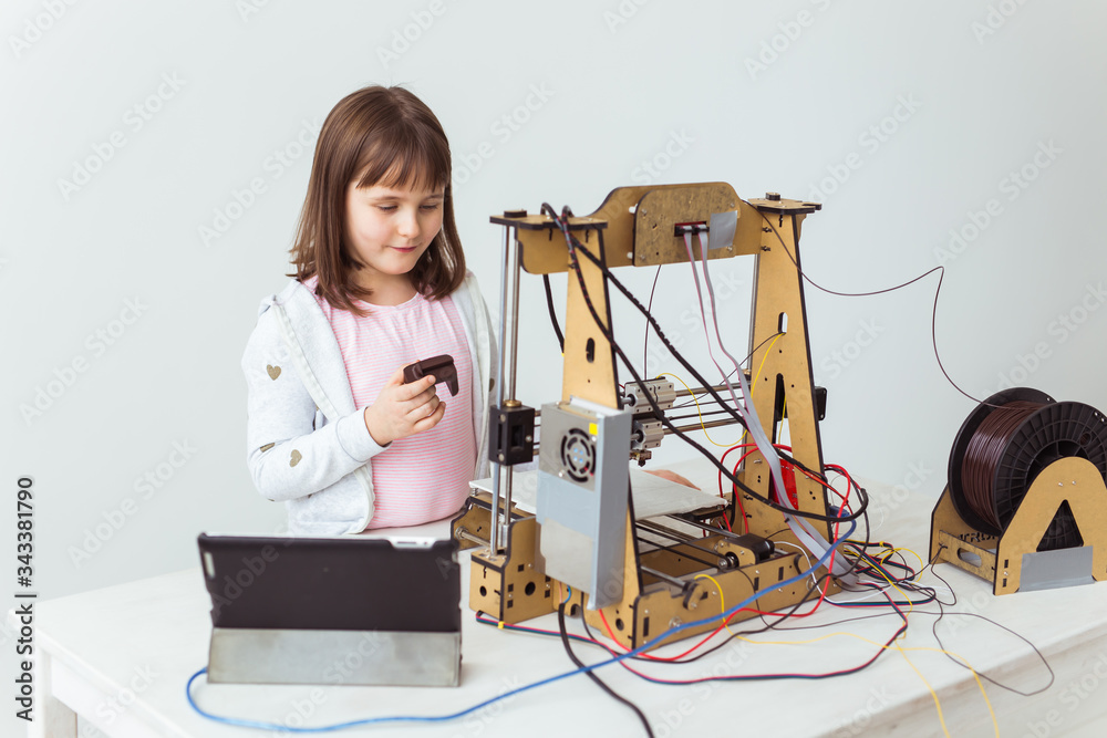 Cute girl with 3d printed shutter shades is watching her 3d printer as ...