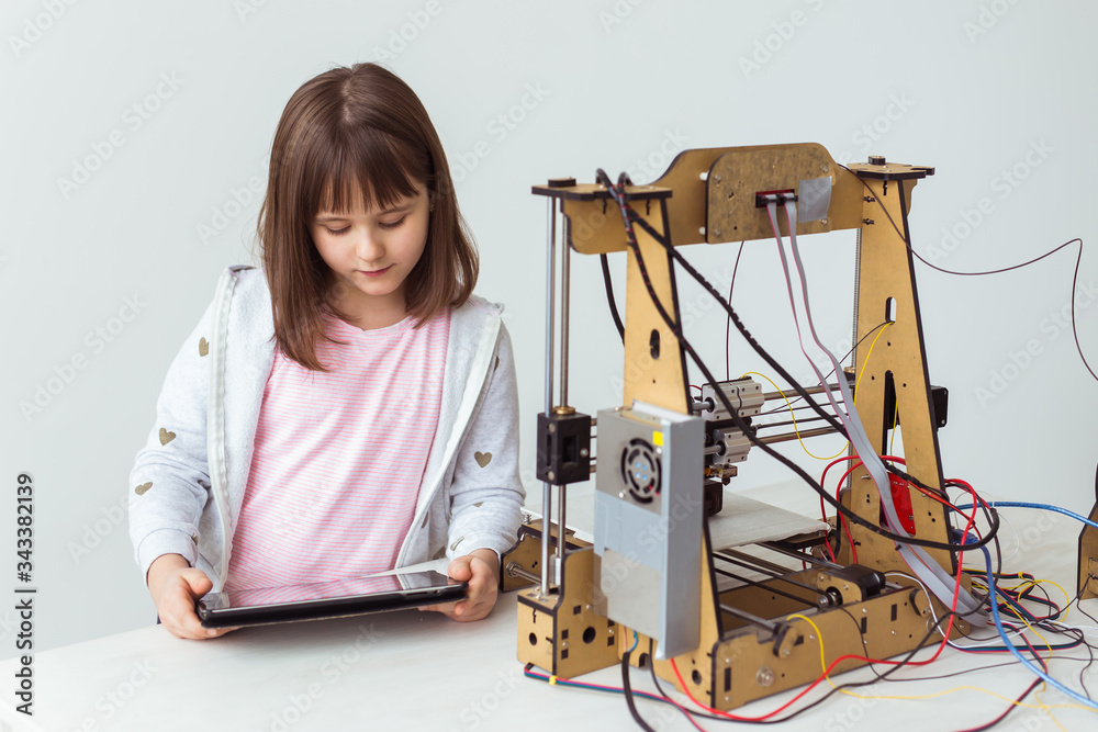 Cute girl with 3d printed shutter shades is watching her 3d printer as ...