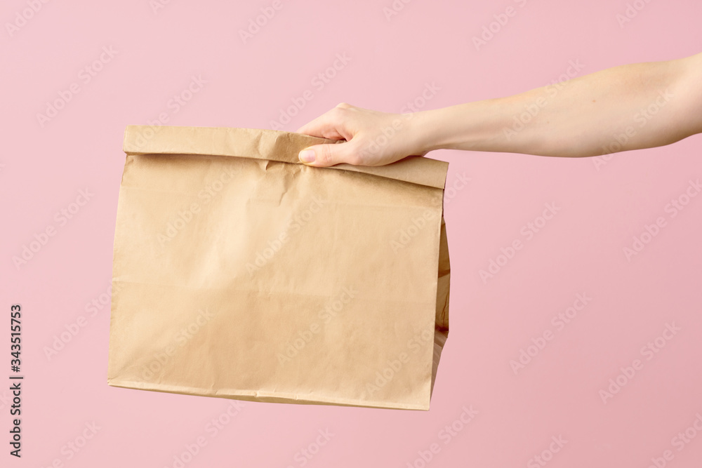 Female hand holding brown clear empty blank paper bag for food delivery ...