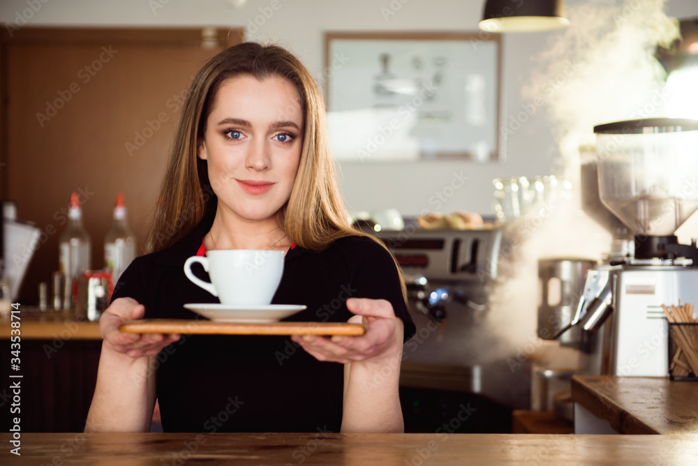 Beautiful female barista is working in coffee shop. Attractive woman is ...