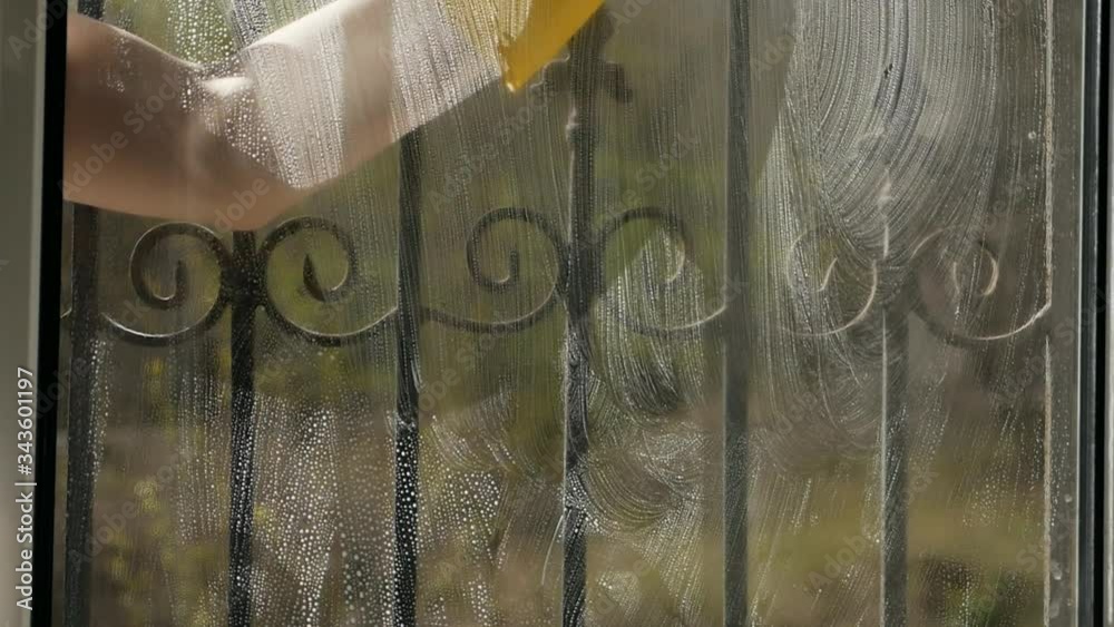 A female hand is washing a window with a rag. Home cleaning, restoring ...