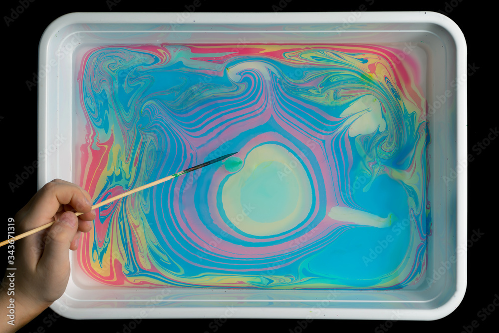 Drawing on the surface of the water. Paper marbling technique. Child's ...