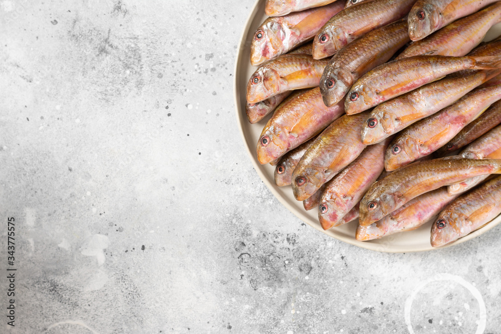 Black sea barabulka fish in a white ceramic bowl on a light gray ...