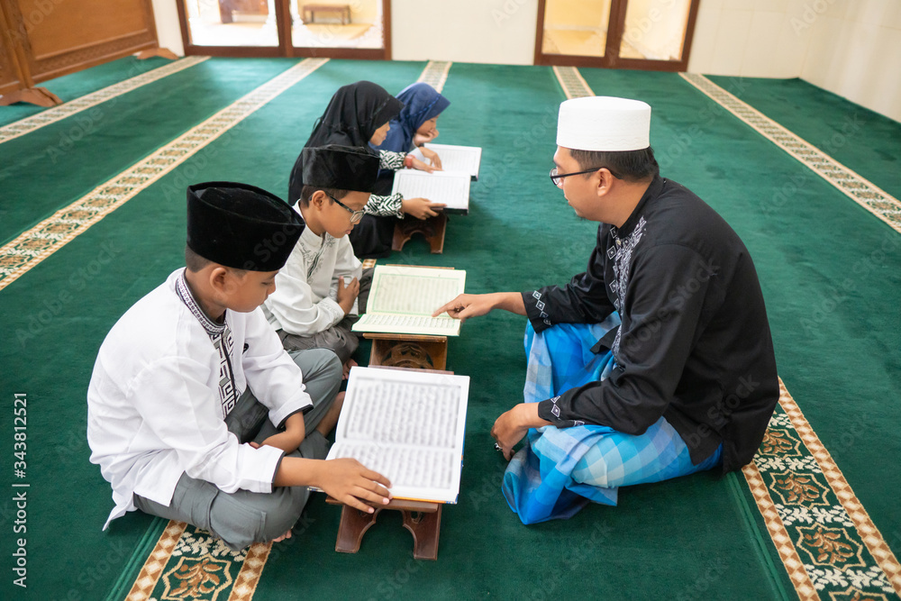 teacher is teaching muslim kid how to read holy quran in the mosque ...