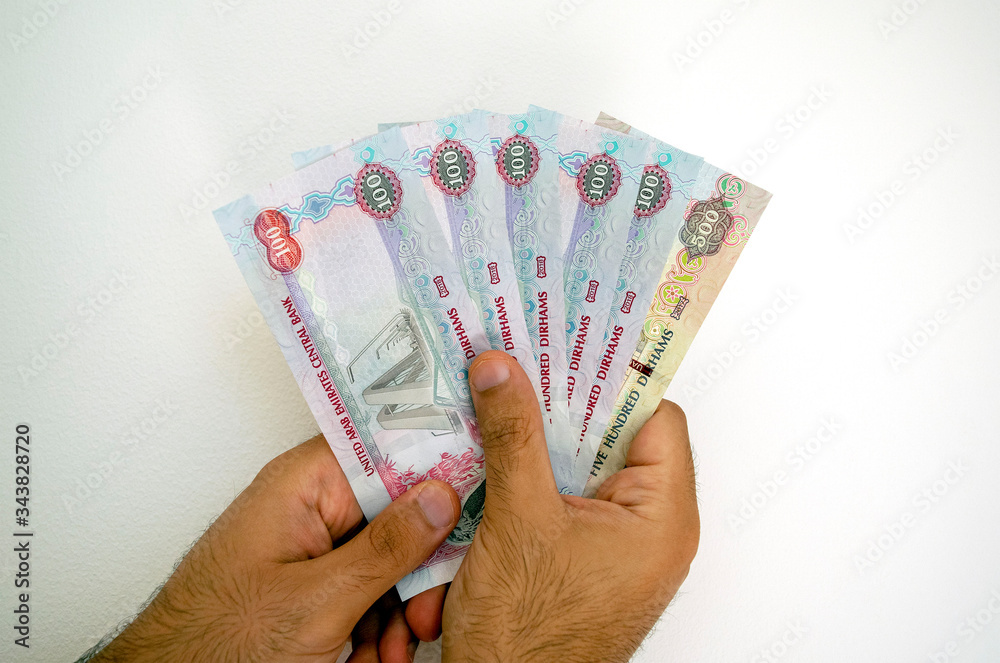 UAE national currency. UAE money banknotes. Young man holds in his ...