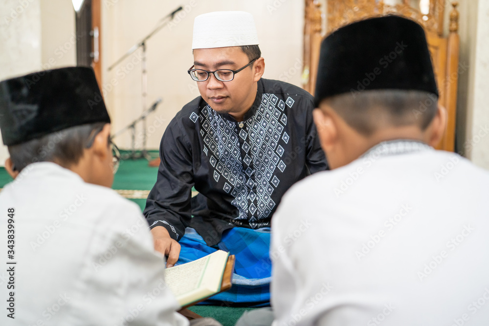teacher is teaching muslim kid how to read holy quran in the mosque ...