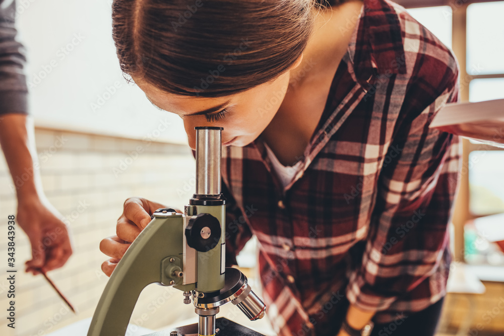 Female student looking through microscope at a science class Stock ...