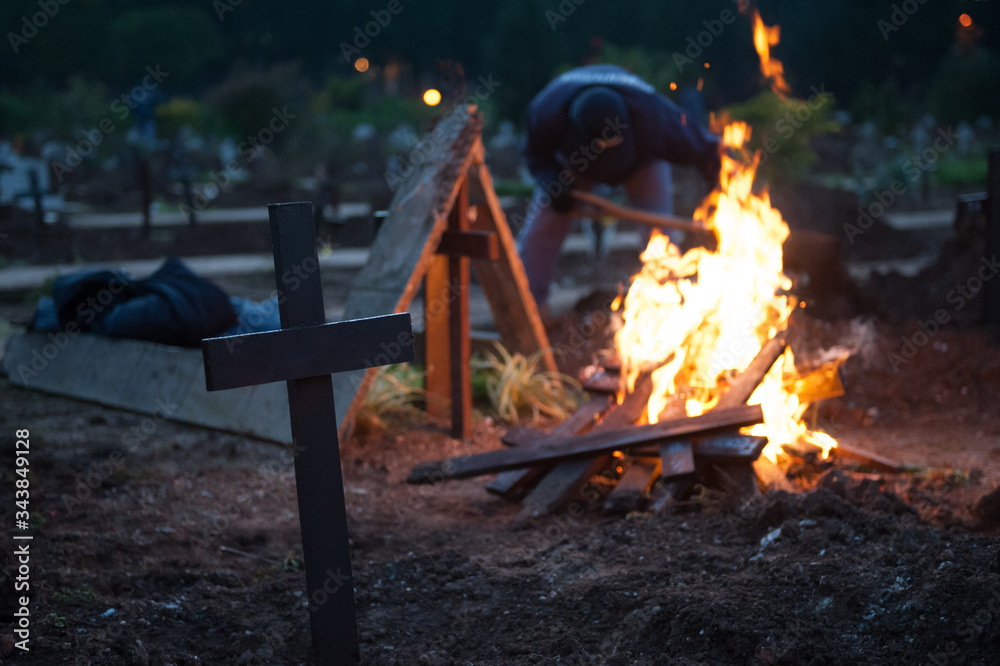 Cross, fire and death. Cemetery workers digging to take out the human ...