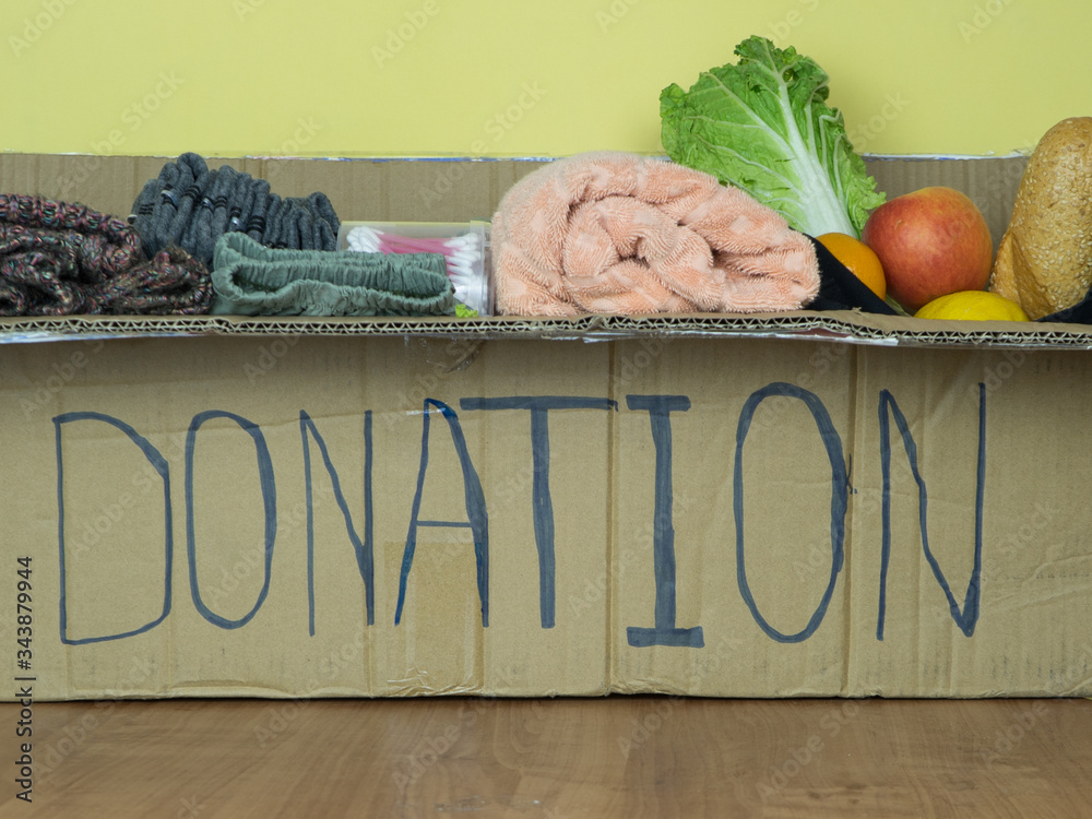 Big donation box with food and clothes insideon yellow background on ...