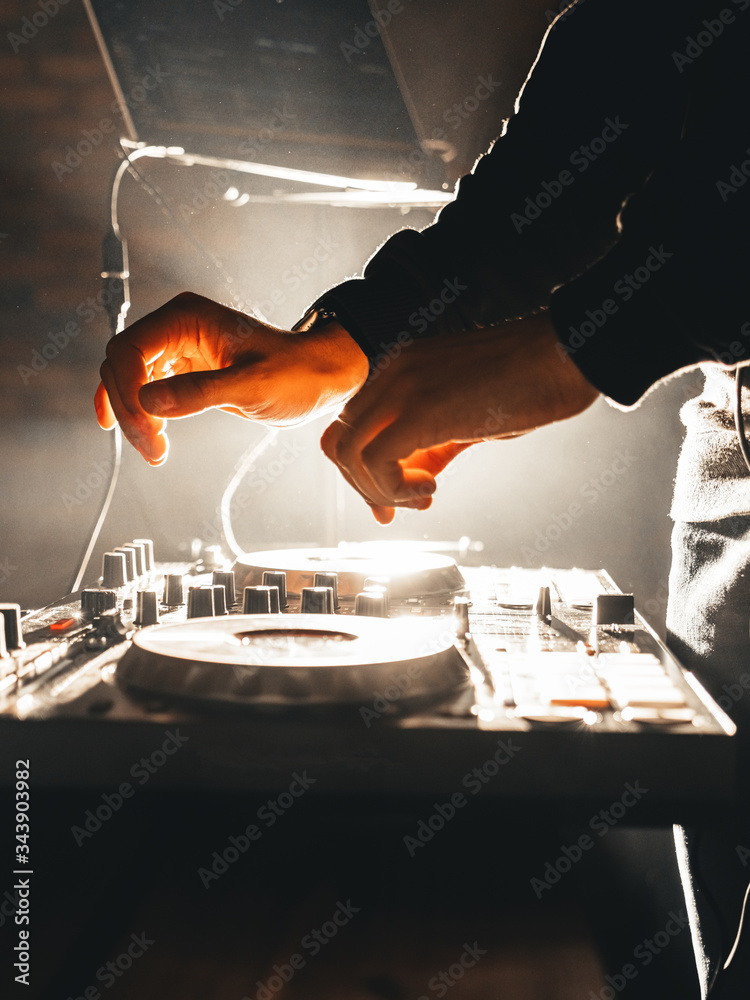 Side view of DJ male hands, playing on mixing console, with white cold ...